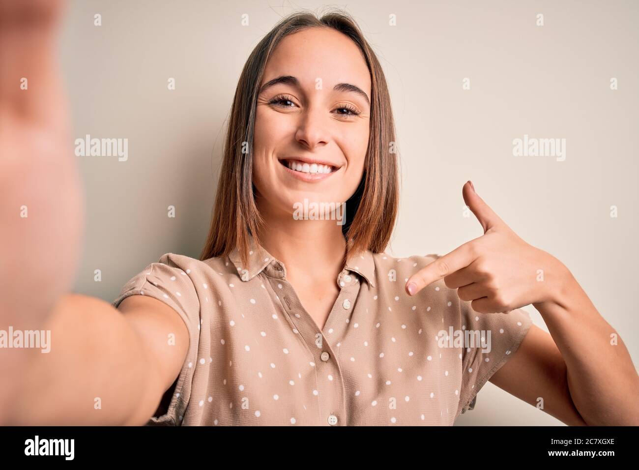 Young beautiful woman wearing summer shirt making selfie by camera over ...