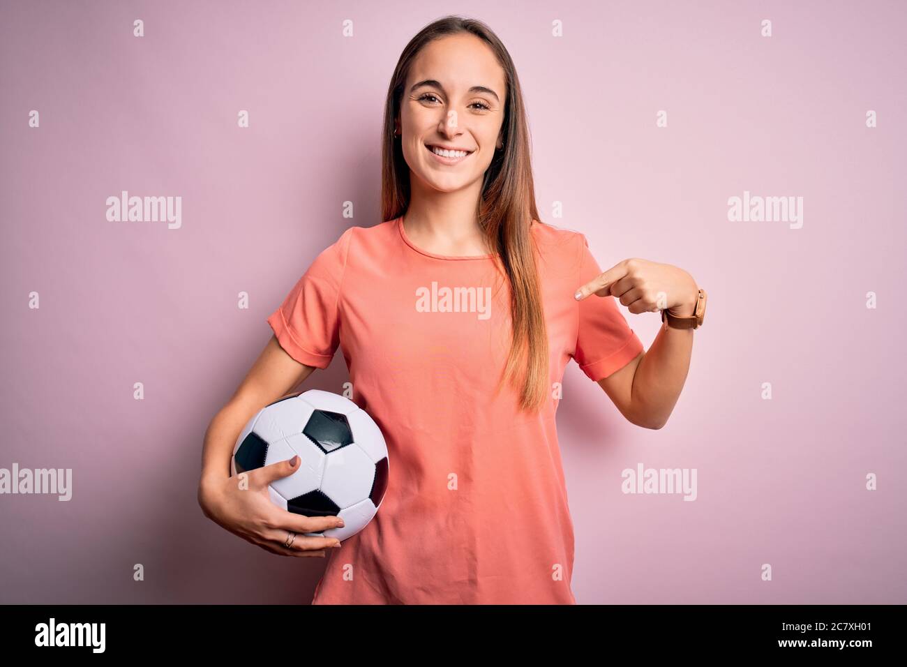 Young beautiful player woman playing soccer holding football ball over ...