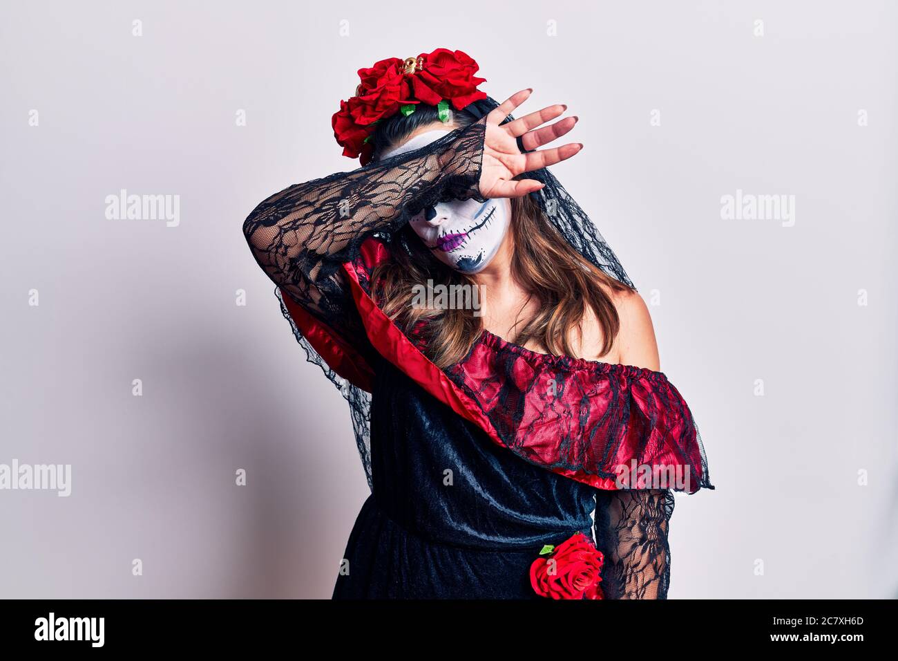 Young woman wearing day of the dead costume over white covering eyes ...