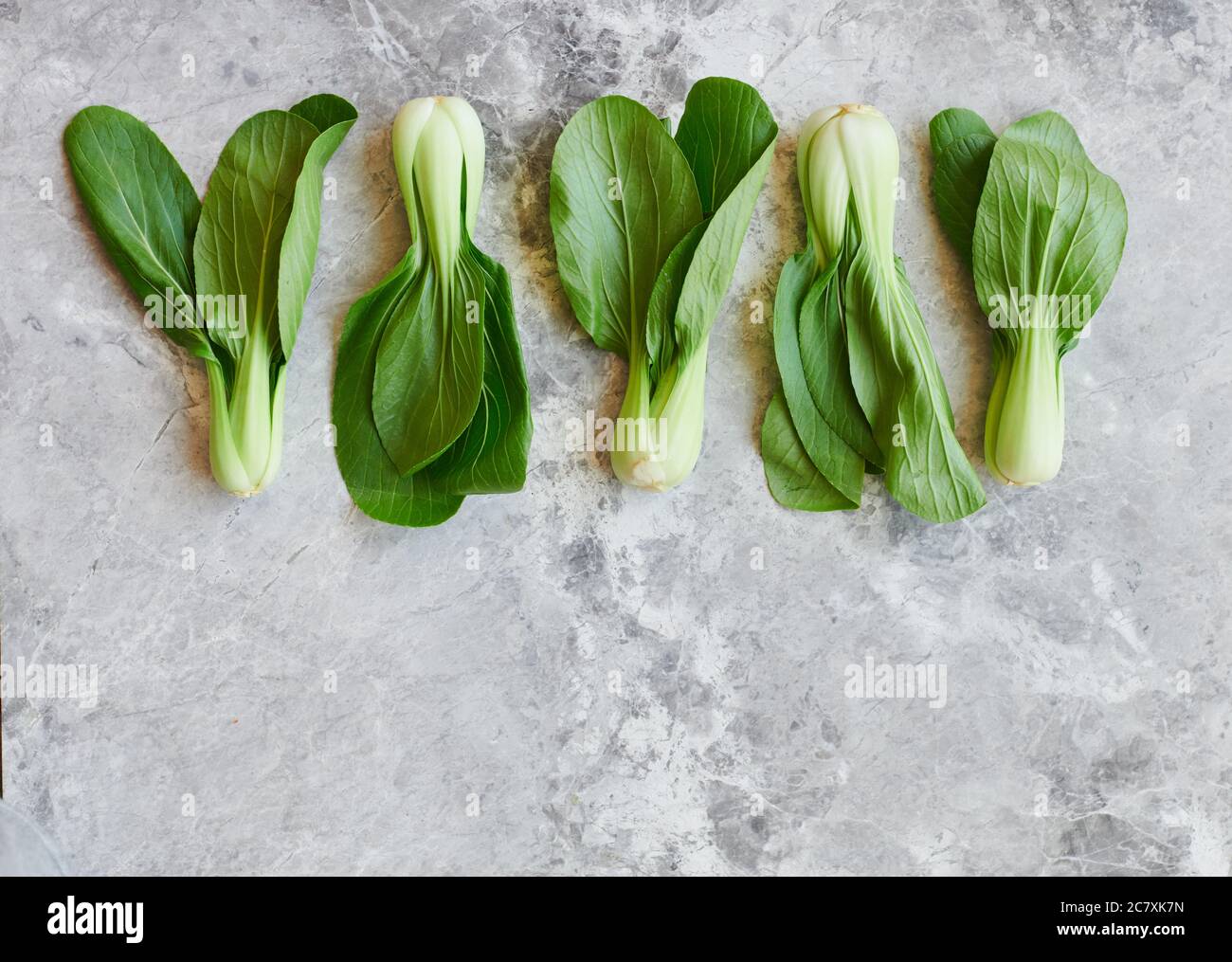 Overhead shot of fresh green pak choi on gray marble surface with space ...