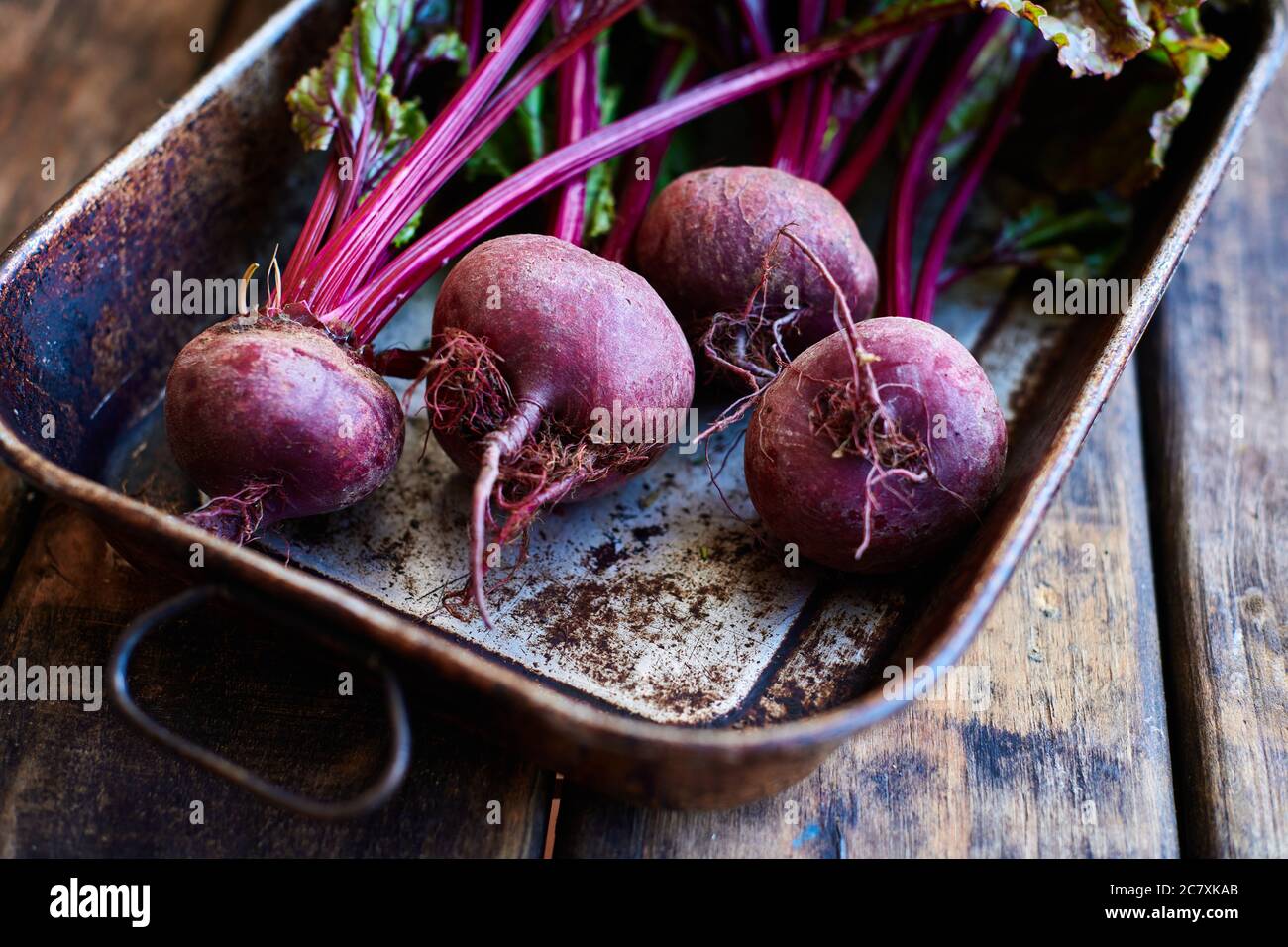 Closeup of fresh organic beetroot on a tray against a wooden surface ...