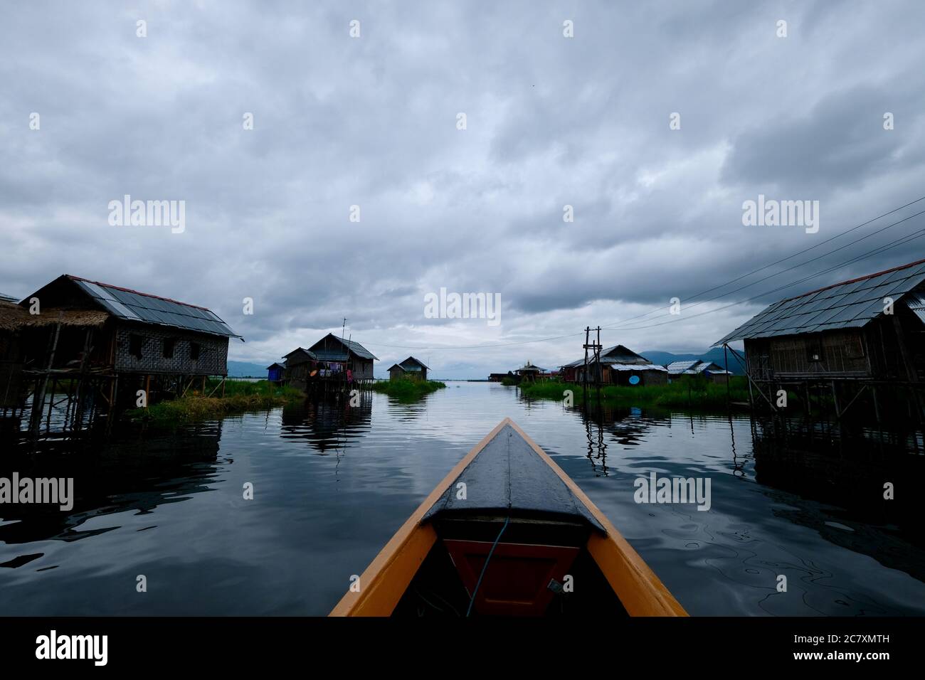 first-person view of boating on Inle lake. Houses above water. Cloudy ...