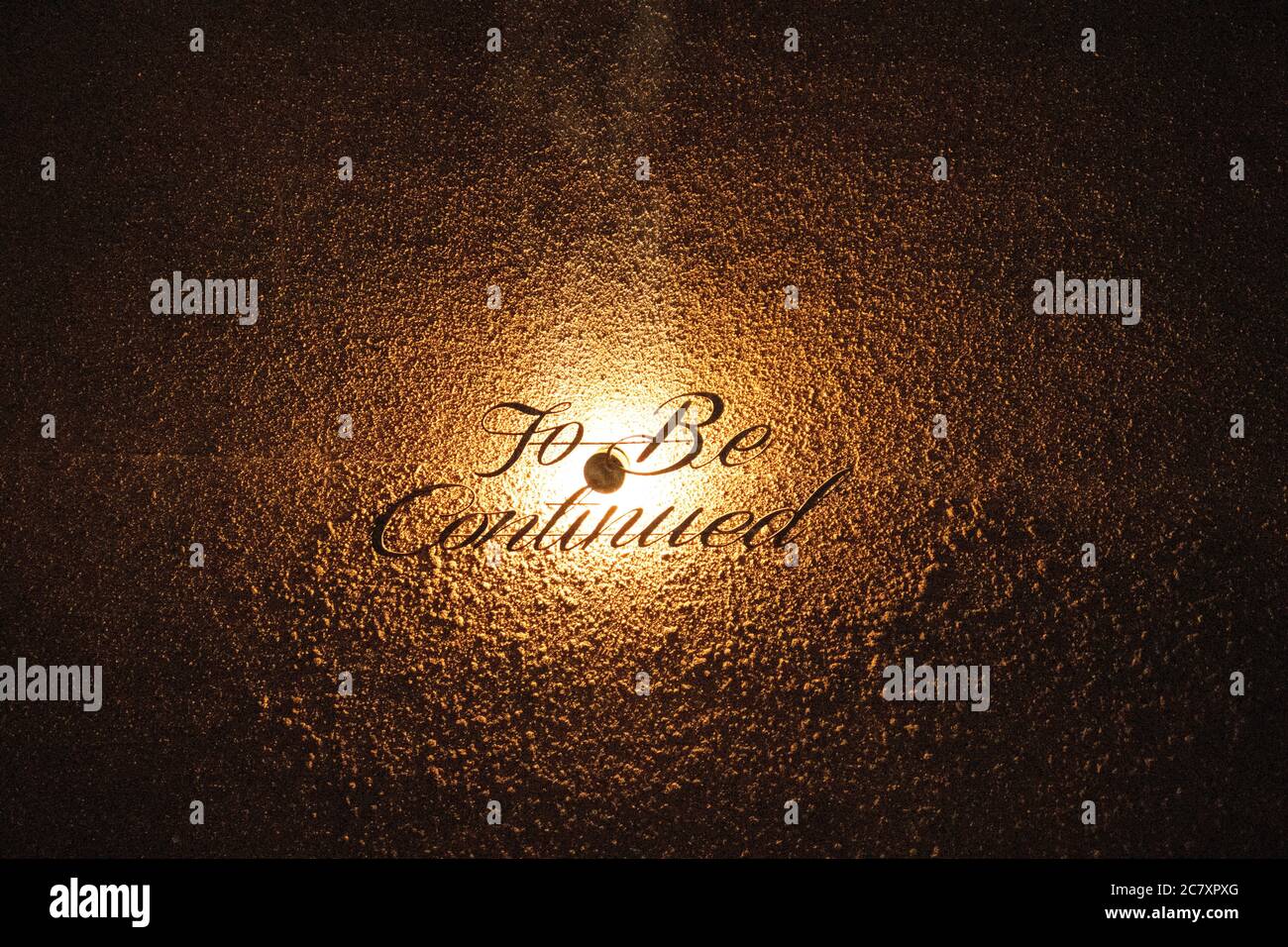 Metal "To Be Continued" inscription on rock in front of a golden light ...