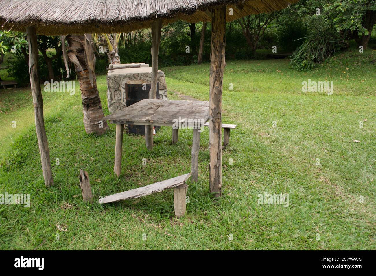 Eye-level shot of a gazebo made from wood and hay in a field of green ...