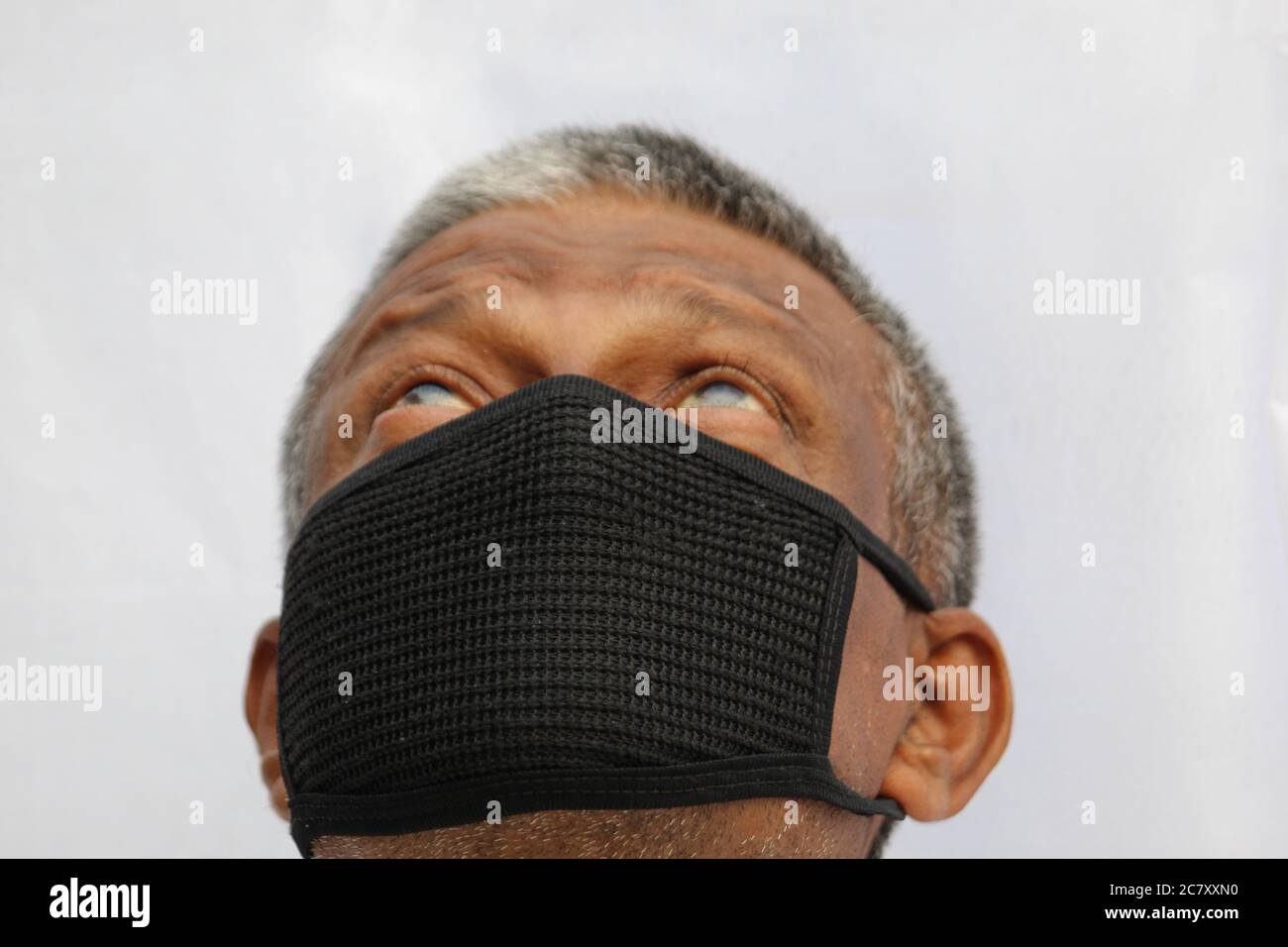 Black protection mask closeup wearing by senior Indian man on white ...