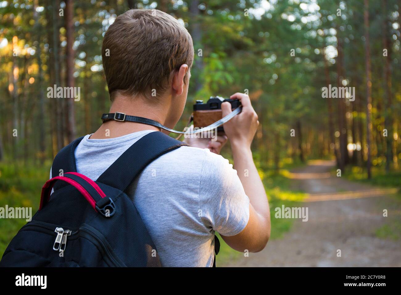 back view of man taking a photo with retro camera in forest Stock Photo ...