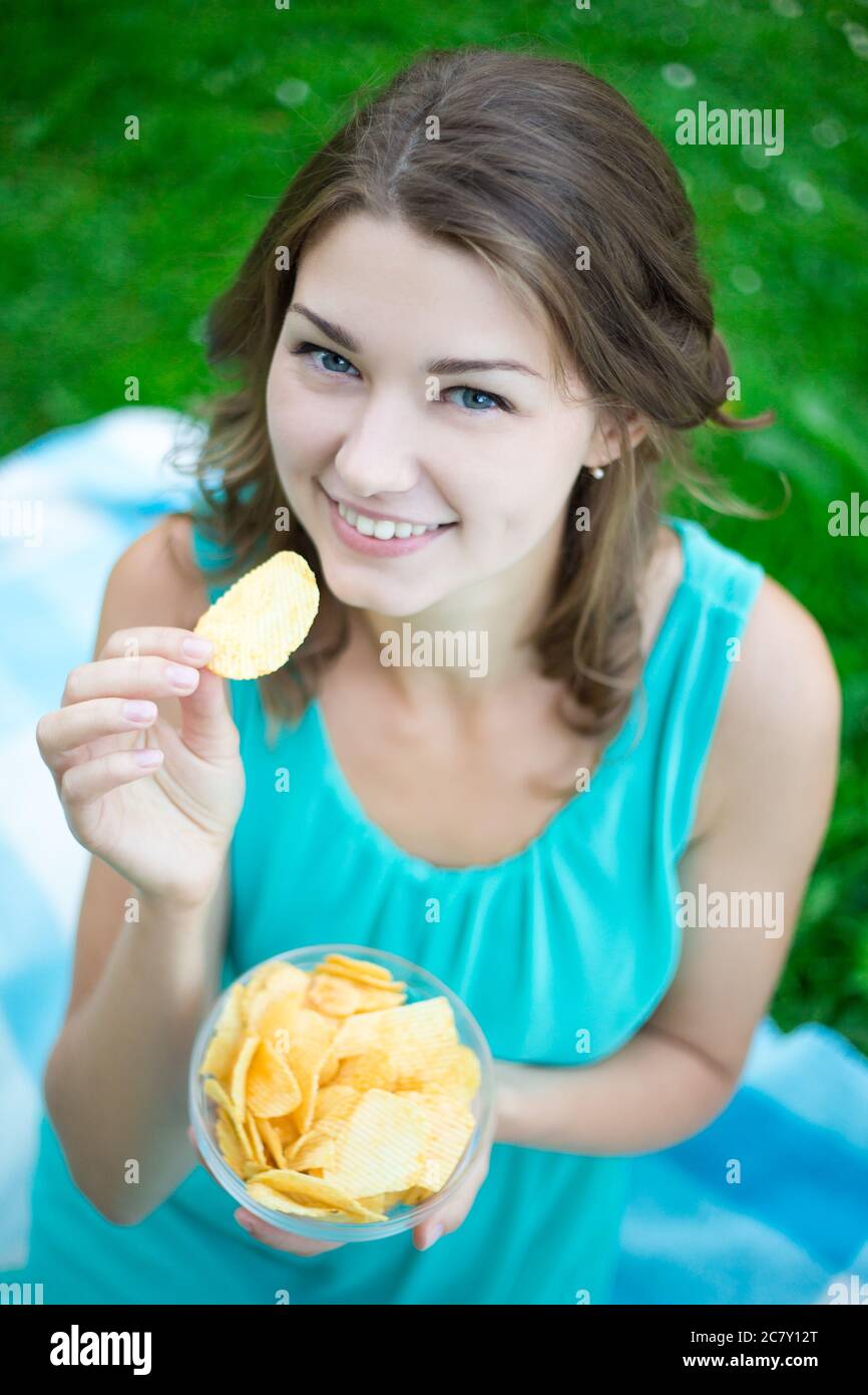 close up portrait of cute young woman eating potato chips Stock Photo ...
