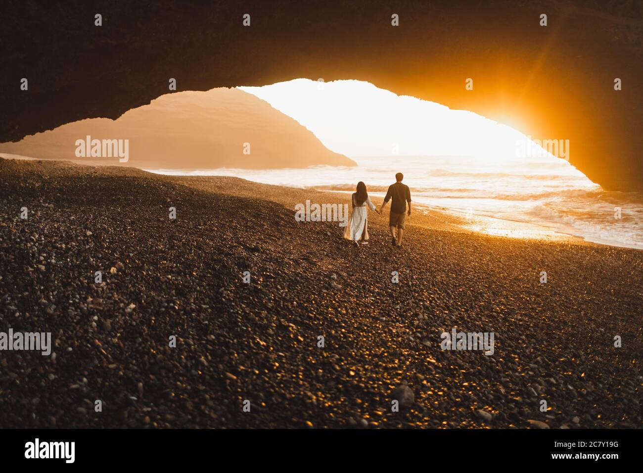 Couple walking under big arch on Legzira ocean beach and enjoying ...