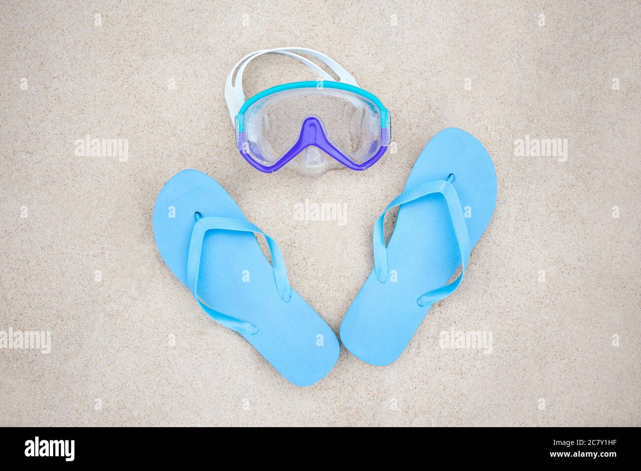 beach concept - close up of blue slippers and diving mask on the sand ...