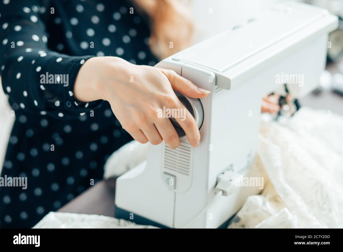 seamstress female sews clothes and put thread in needle. Workplace of ...
