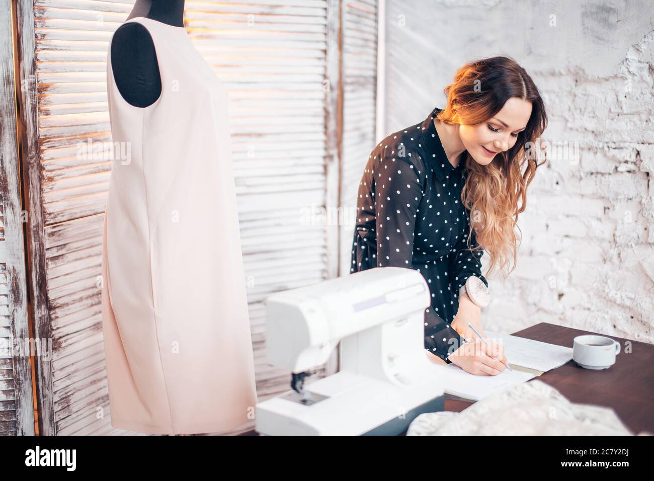 tailor writing in notebook at workspace with sewing machine and ...