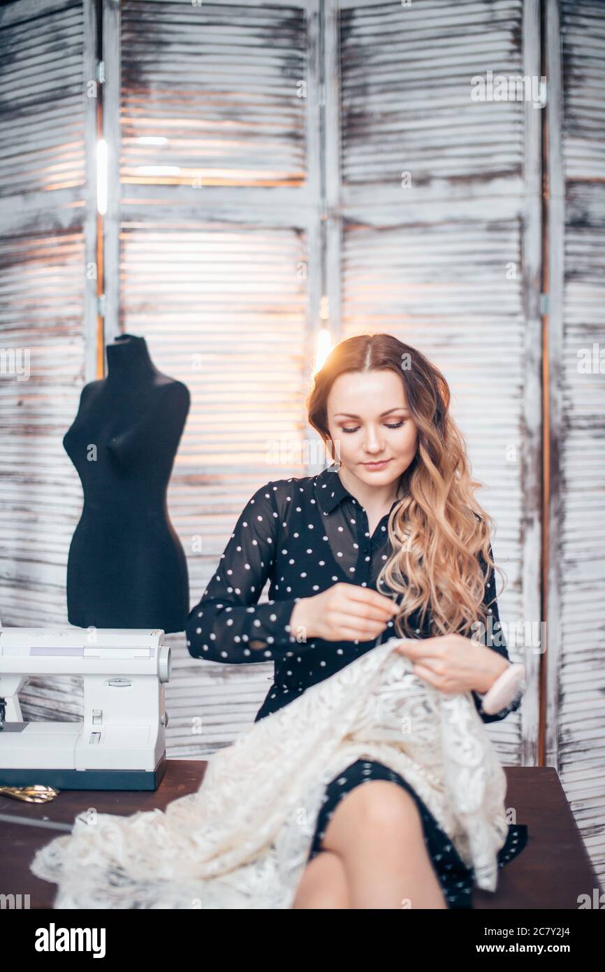 young seamstress sewing a white cloth tailoring according to the ...