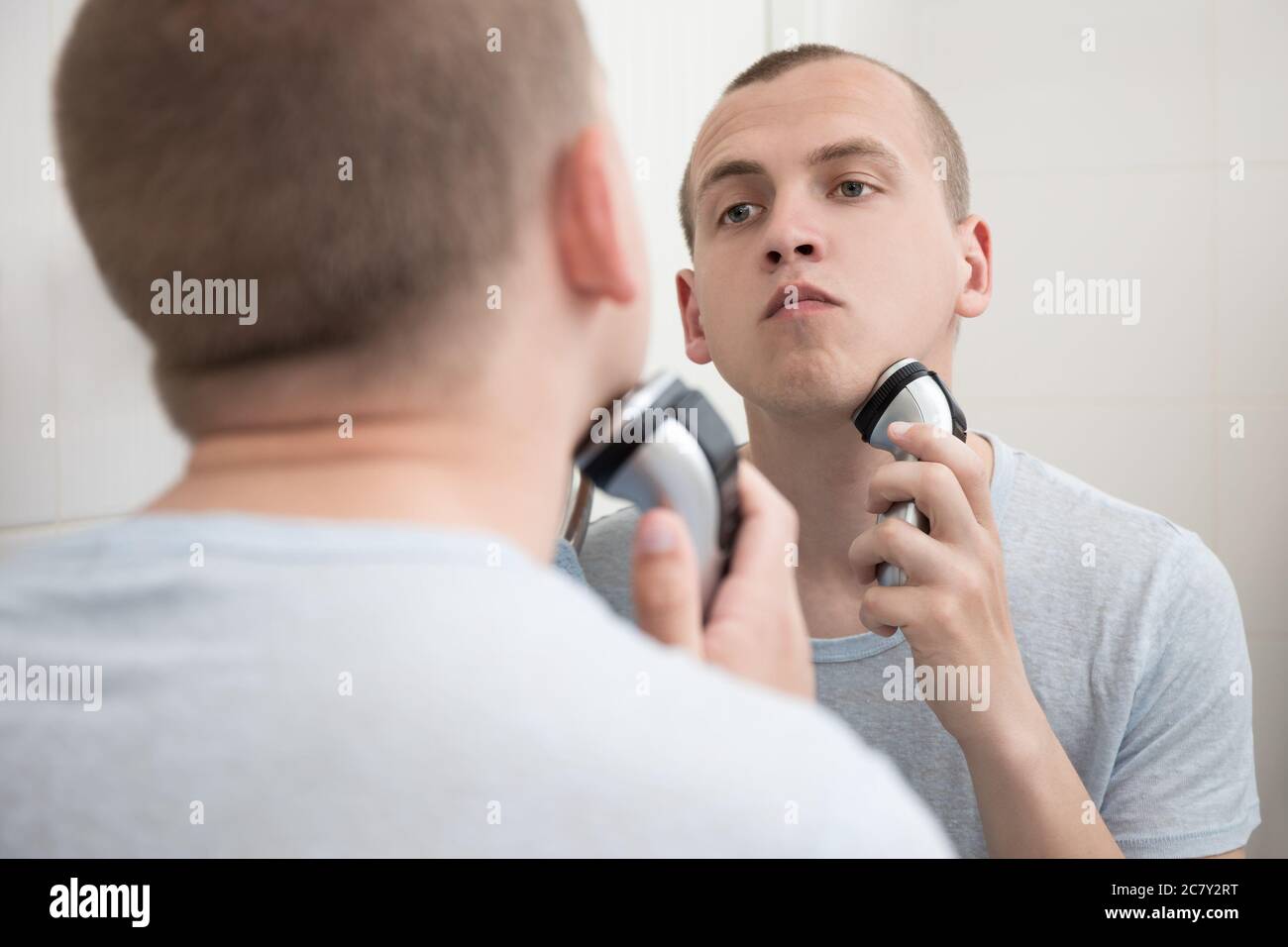 handsome man shaving with electric razor in bathroom Stock Photo - Alamy