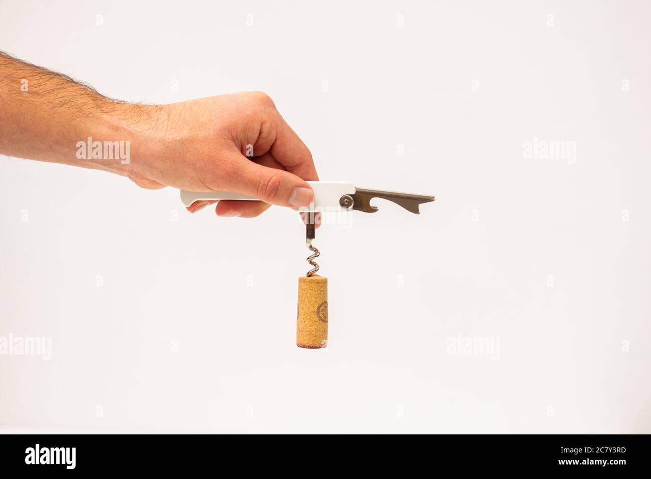 Hand of a man holding a corkscrew with a cork stopper isolated on white ...