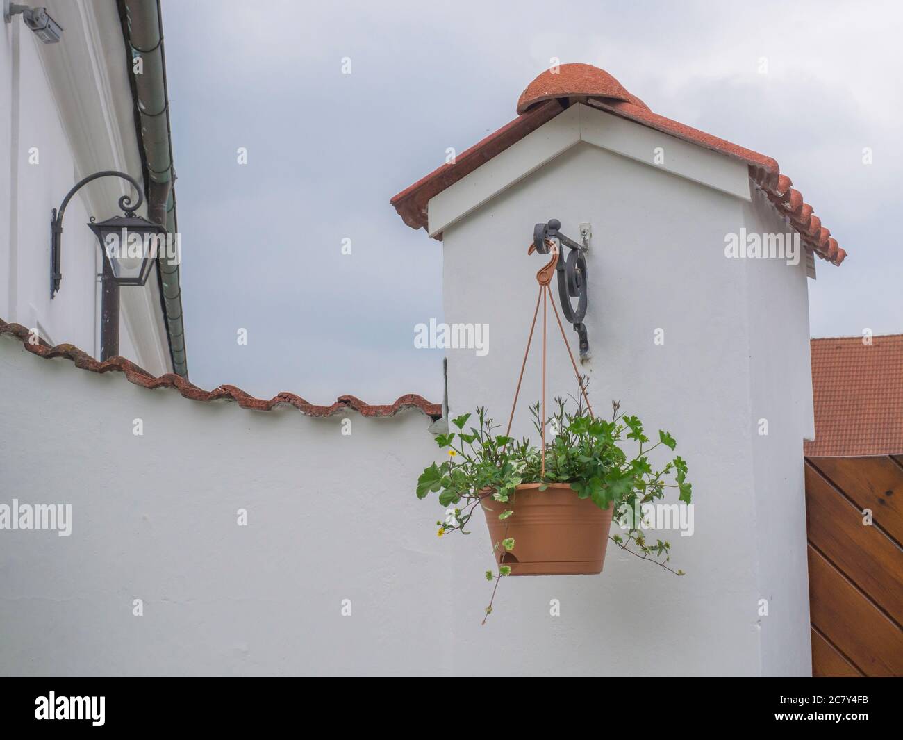 Decorative hanging flower pot in front of old white gate wall of farm ...