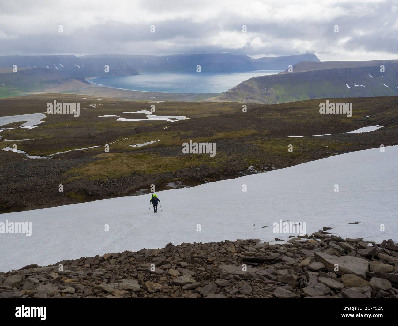 Lonely man hiker with heavy backpack walking on snow field in west ...