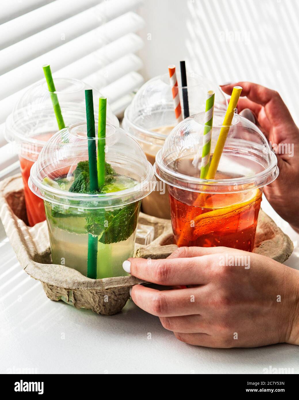 Various summer cold drinks and cocktails in a paper holder in women's ...