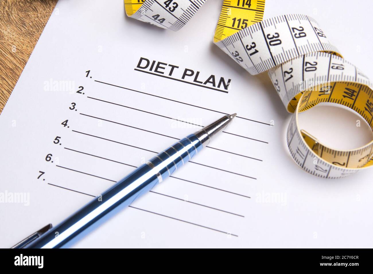 close up of paper with blank diet plan, pen and yellow measure tape ...