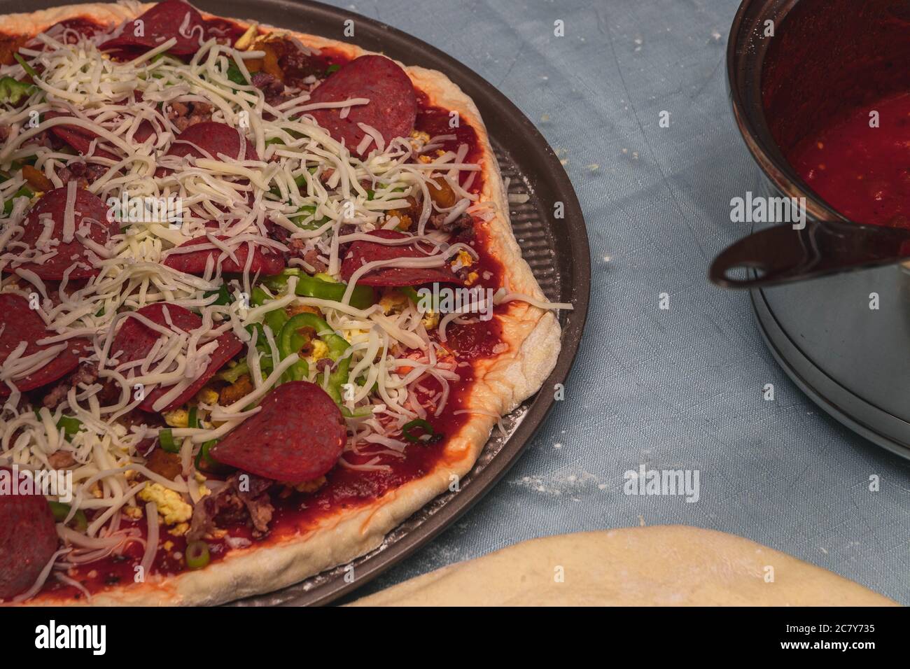 Uncooked pepperoni pizza with a sauce in a pot on a kitchen table Stock ...