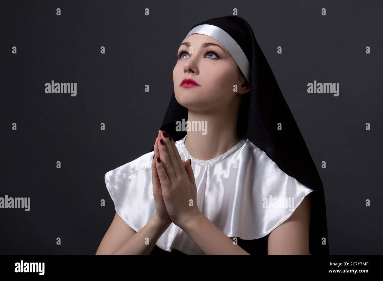 beautiful woman nun with red lips praying over grey background Stock ...