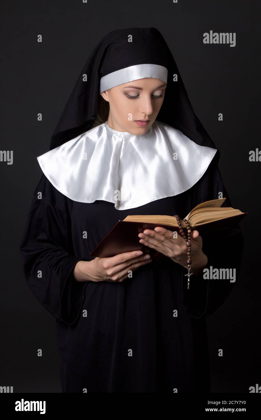 young woman nun reading bible over grey background Stock Photo - Alamy