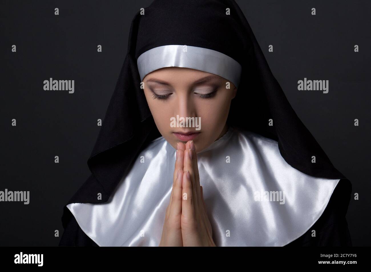 portrait of young beautiful praying nun over grey background Stock ...