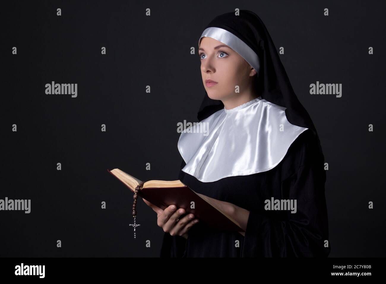 religion concept - young beautiful woman nun reading bible over grey ...