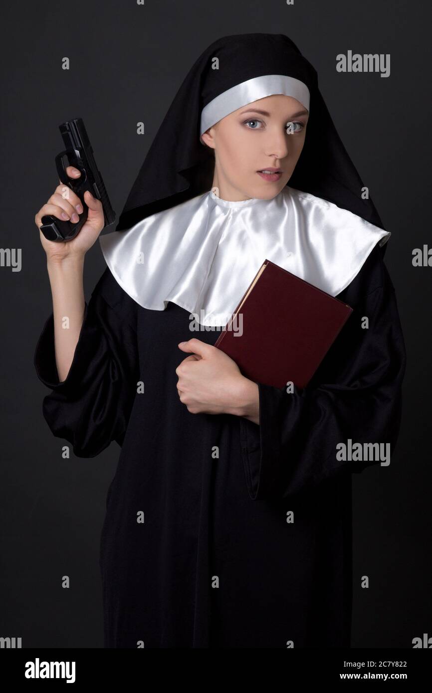 young woman nun with bible and gun over grey Stock Photo - Alamy