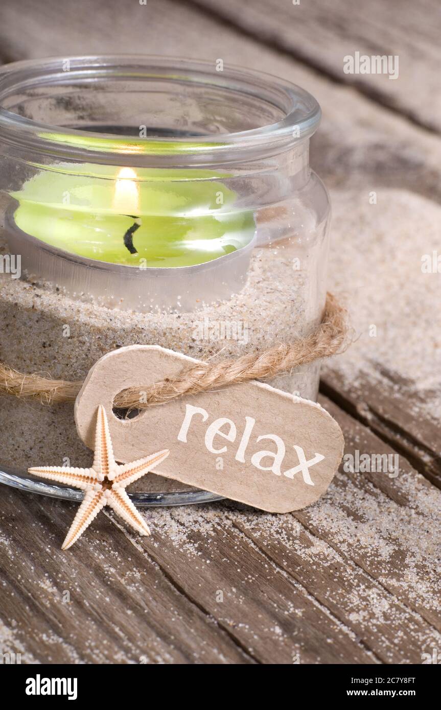 Tealight glass at the beach with lettering relax Stock Photo - Alamy