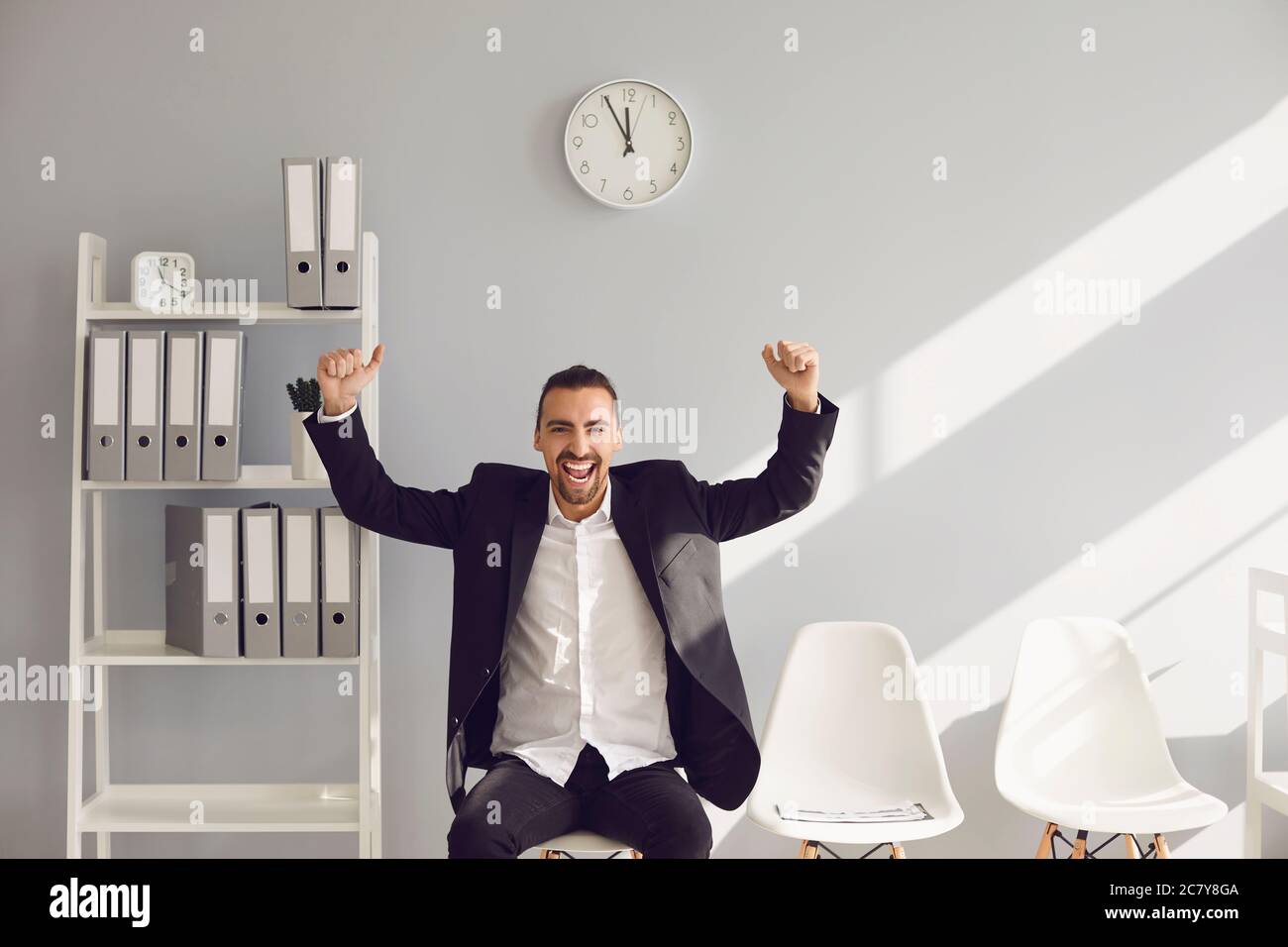 Happy employee rejoices at a successful interview raised his hands up ...