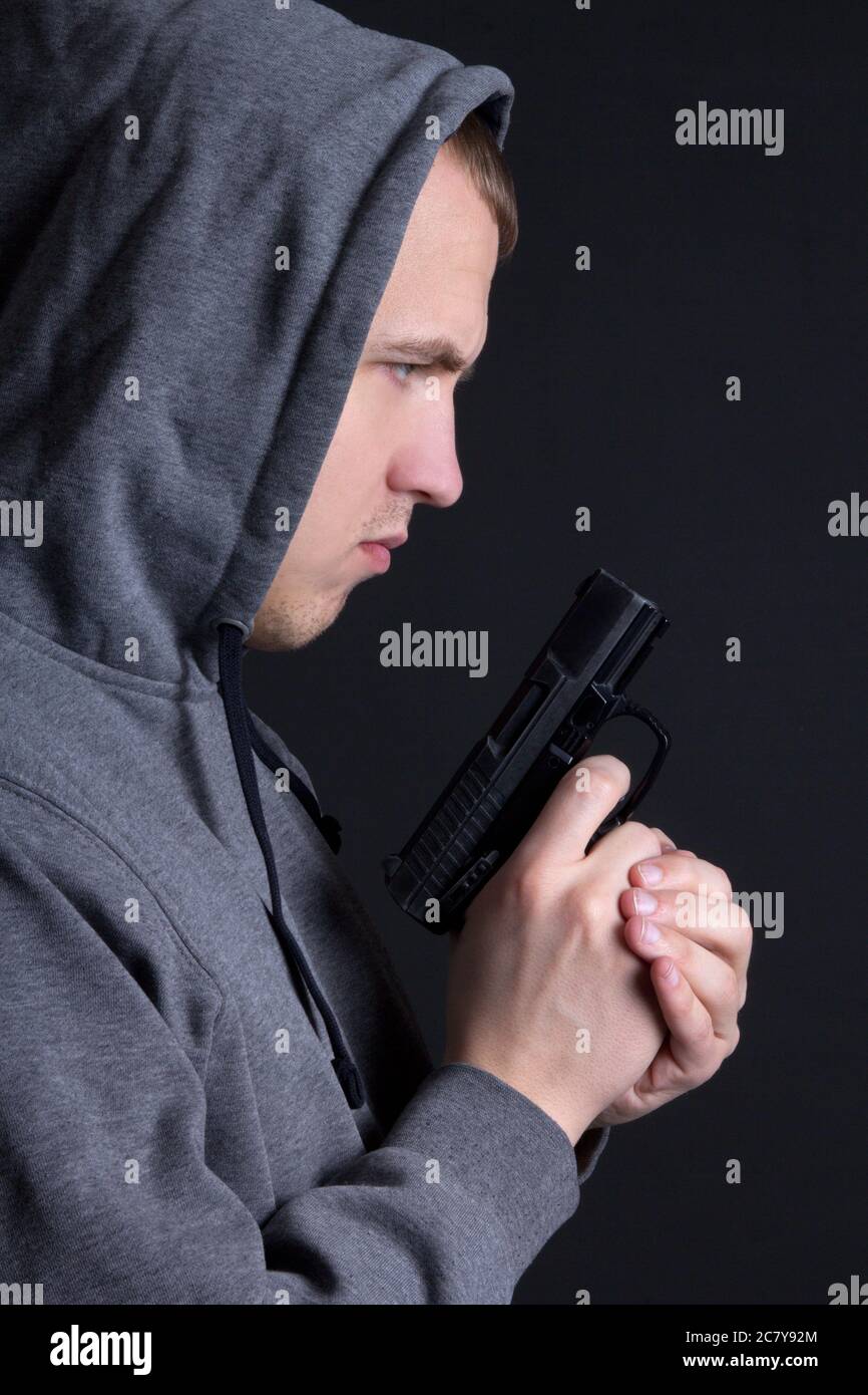 profile of man criminal with gun over grey background Stock Photo - Alamy
