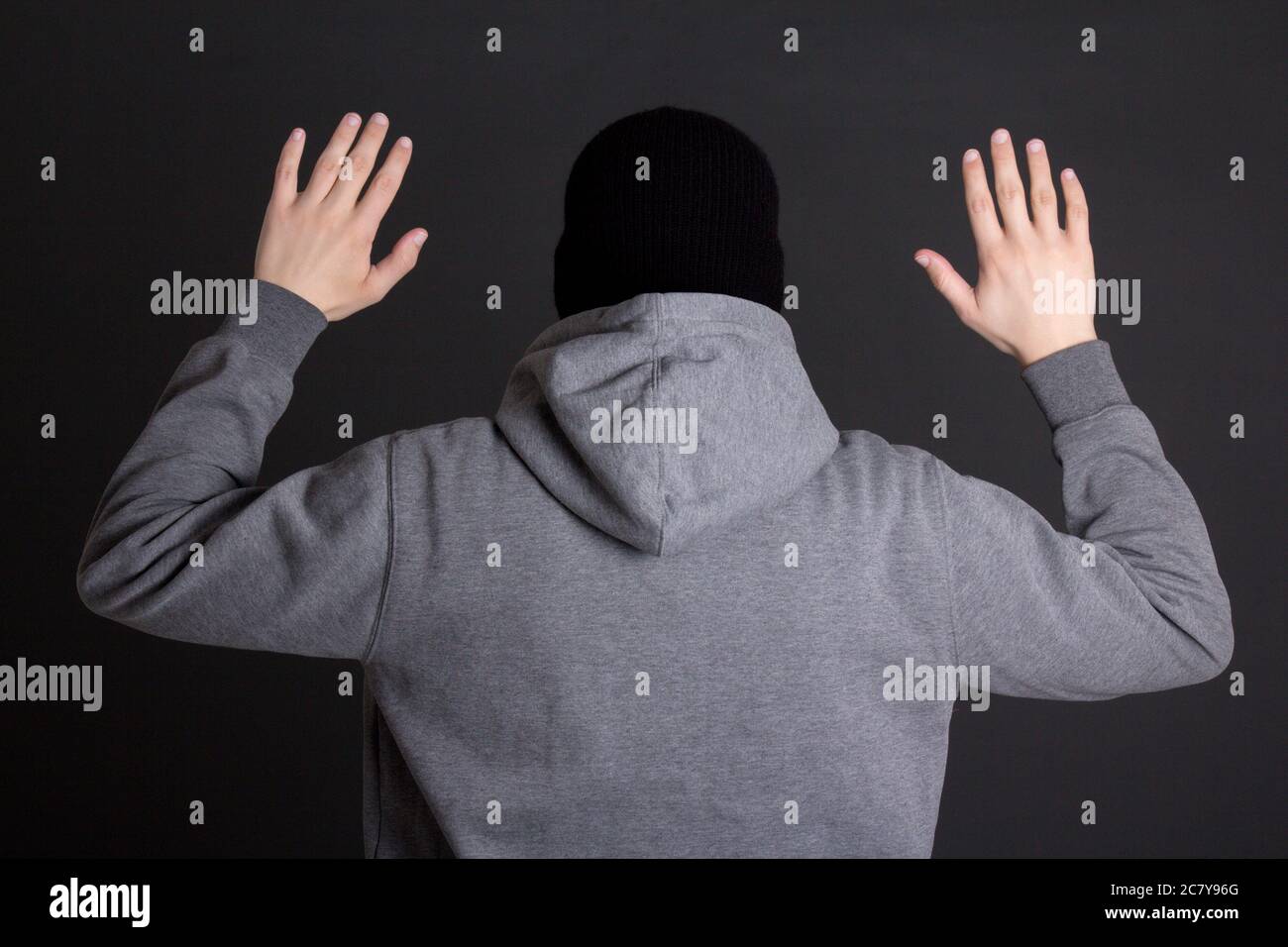 back view of man in black mask holding hands up over grey background ...