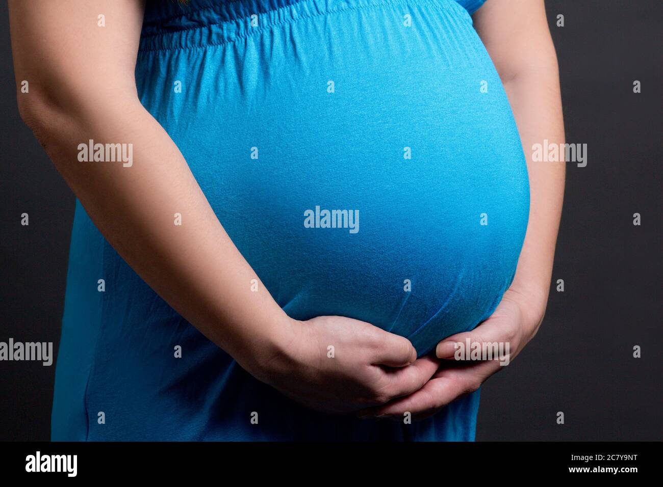 pregnant woman's belly in blue dress over grey background Stock Photo ...