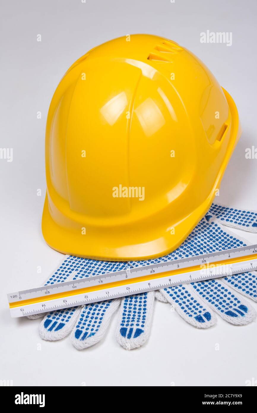 close up of builder's tools - helmet, work gloves and ruler over white ...
