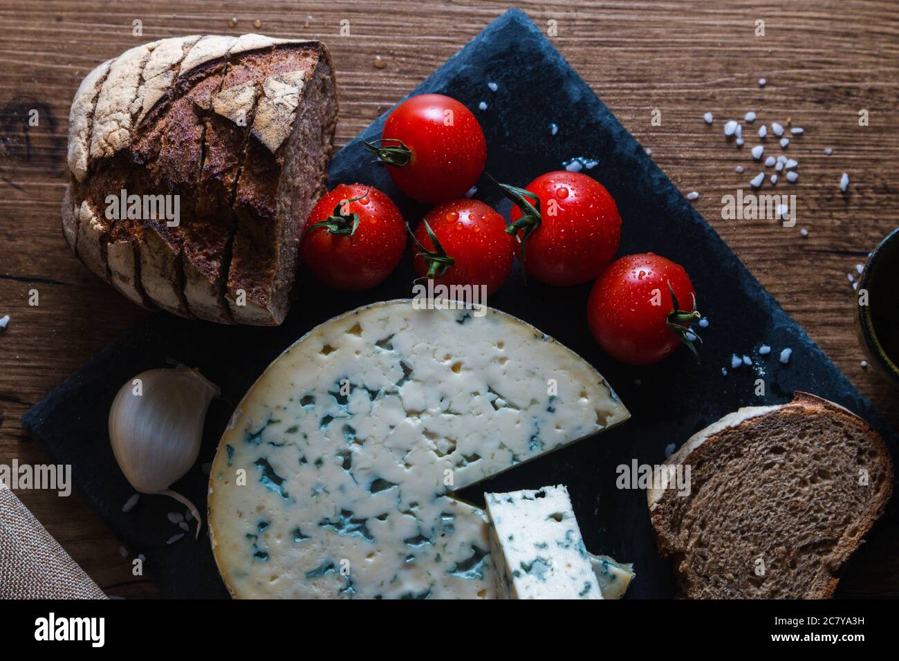 Round blue cheese surrounded by bread, tomatoes and garlic Stock Photo ...