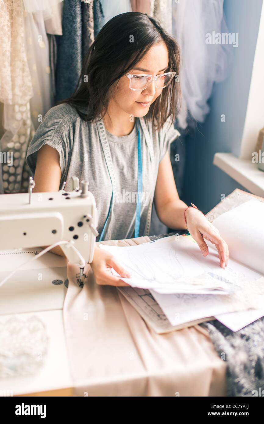 Close up. hands woman Tailor working cutting a roll of fabric on which ...