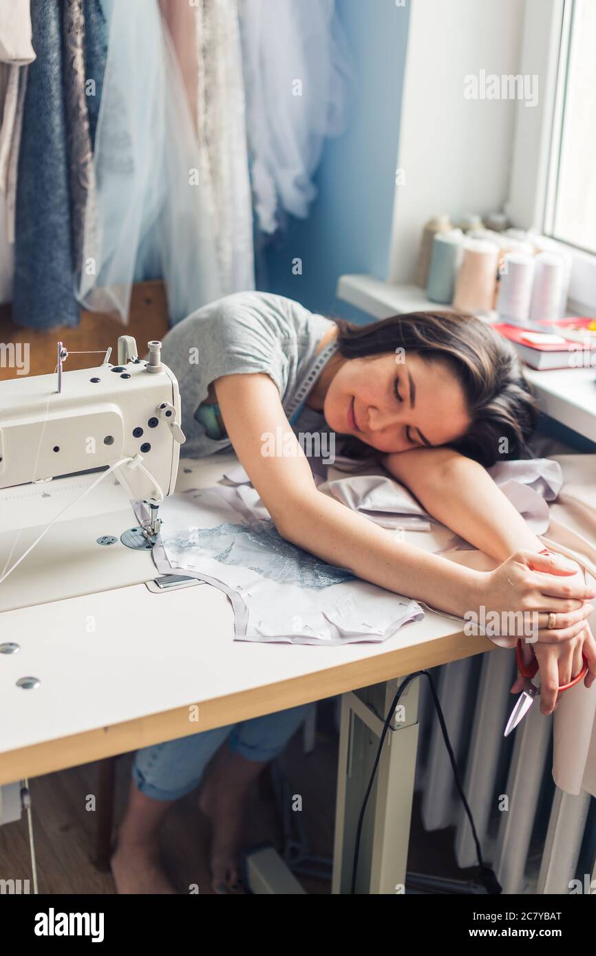 Young woman is asleep by her sewing machine. Tired seamstress having ...