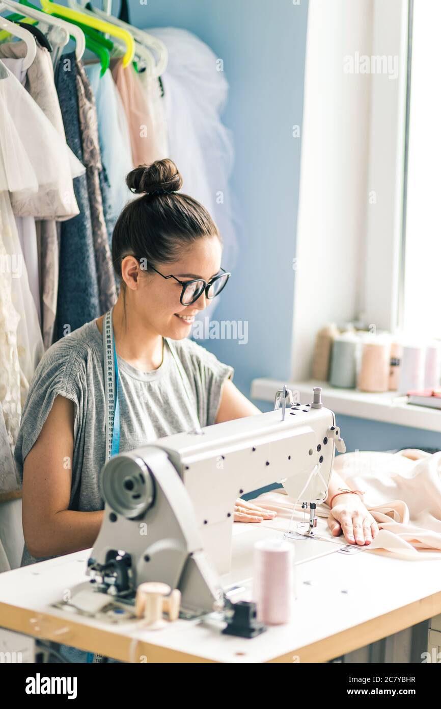 closeup portrait of young woman seamstress sitting and sews on sewing ...
