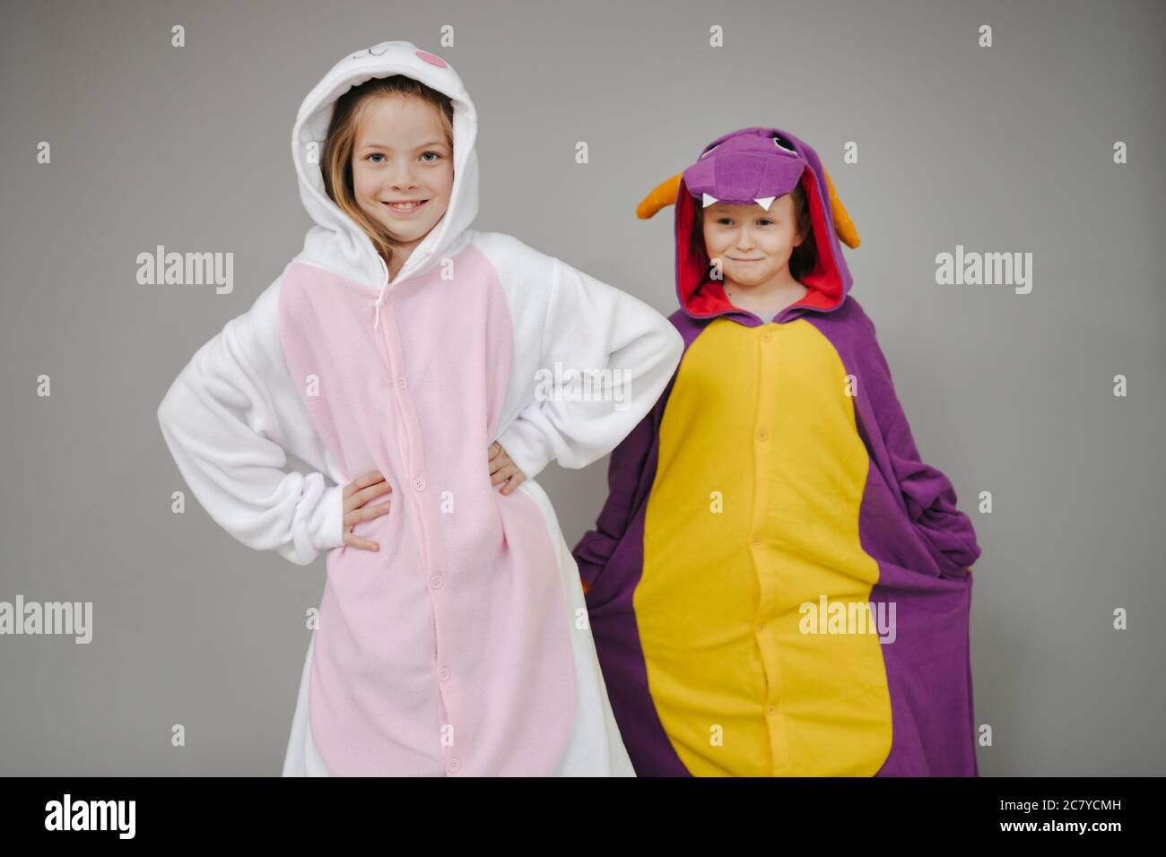 two girls dressed as rabbit and dragon posing in front of grey ...