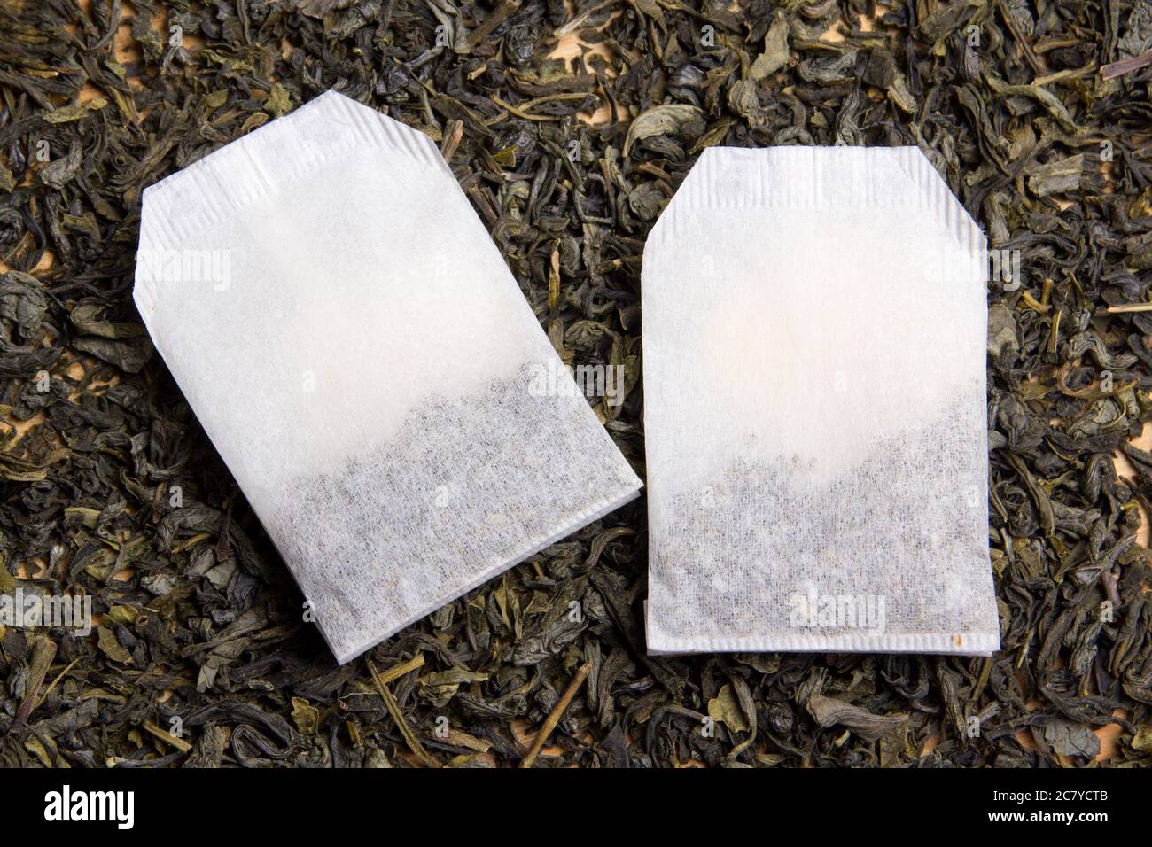 two tea bags over dried tea leaves background Stock Photo - Alamy