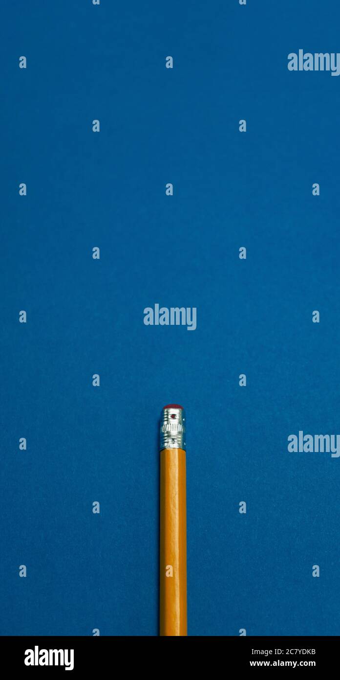 Vertical closeup shot of a pencil with an eraser on a blue background ...