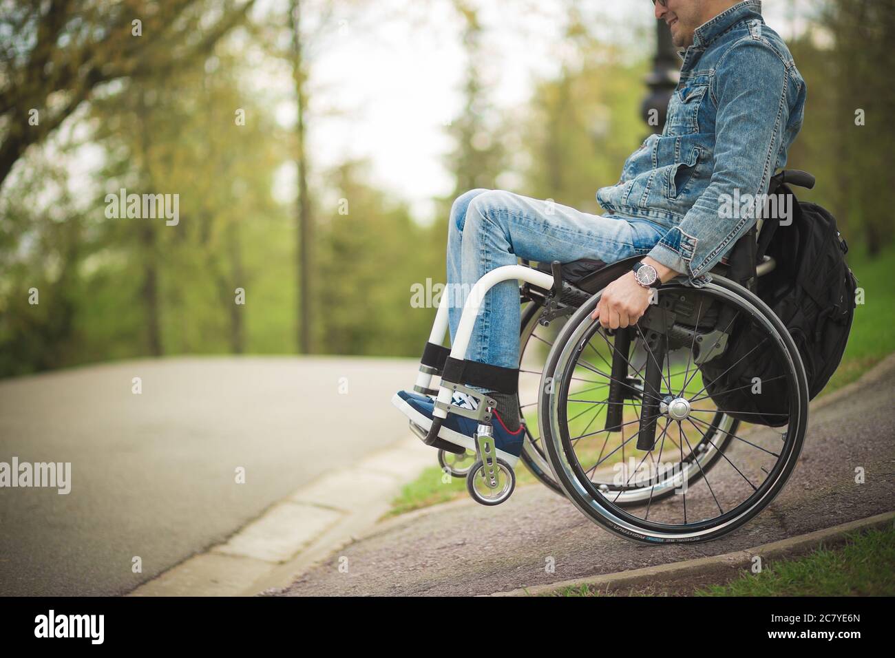 male hand on wheel of wheelchair during walk in park Stock Photo - Alamy