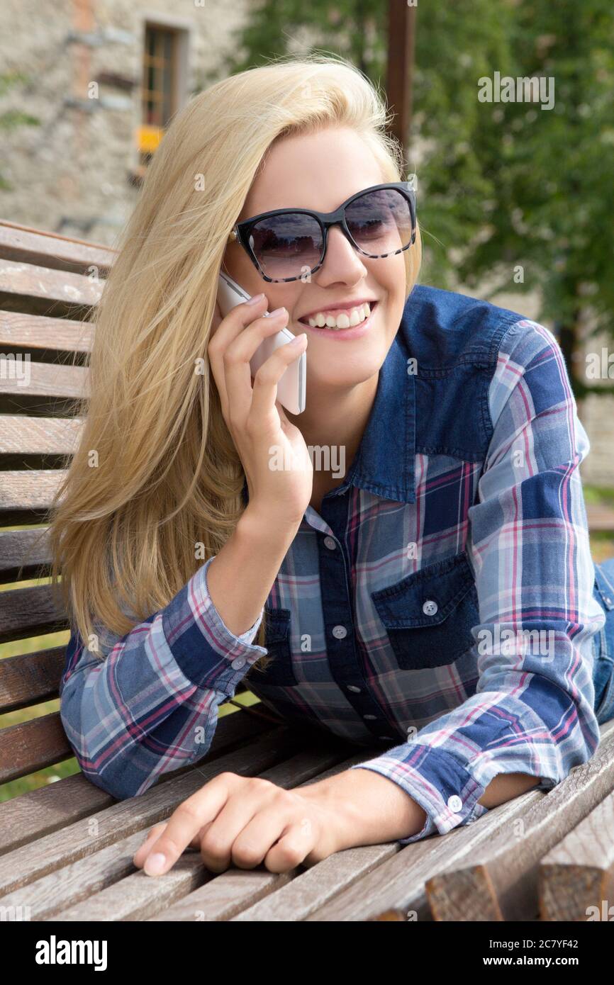 young beautiful woman calling by phone on bench in park Stock Photo - Alamy