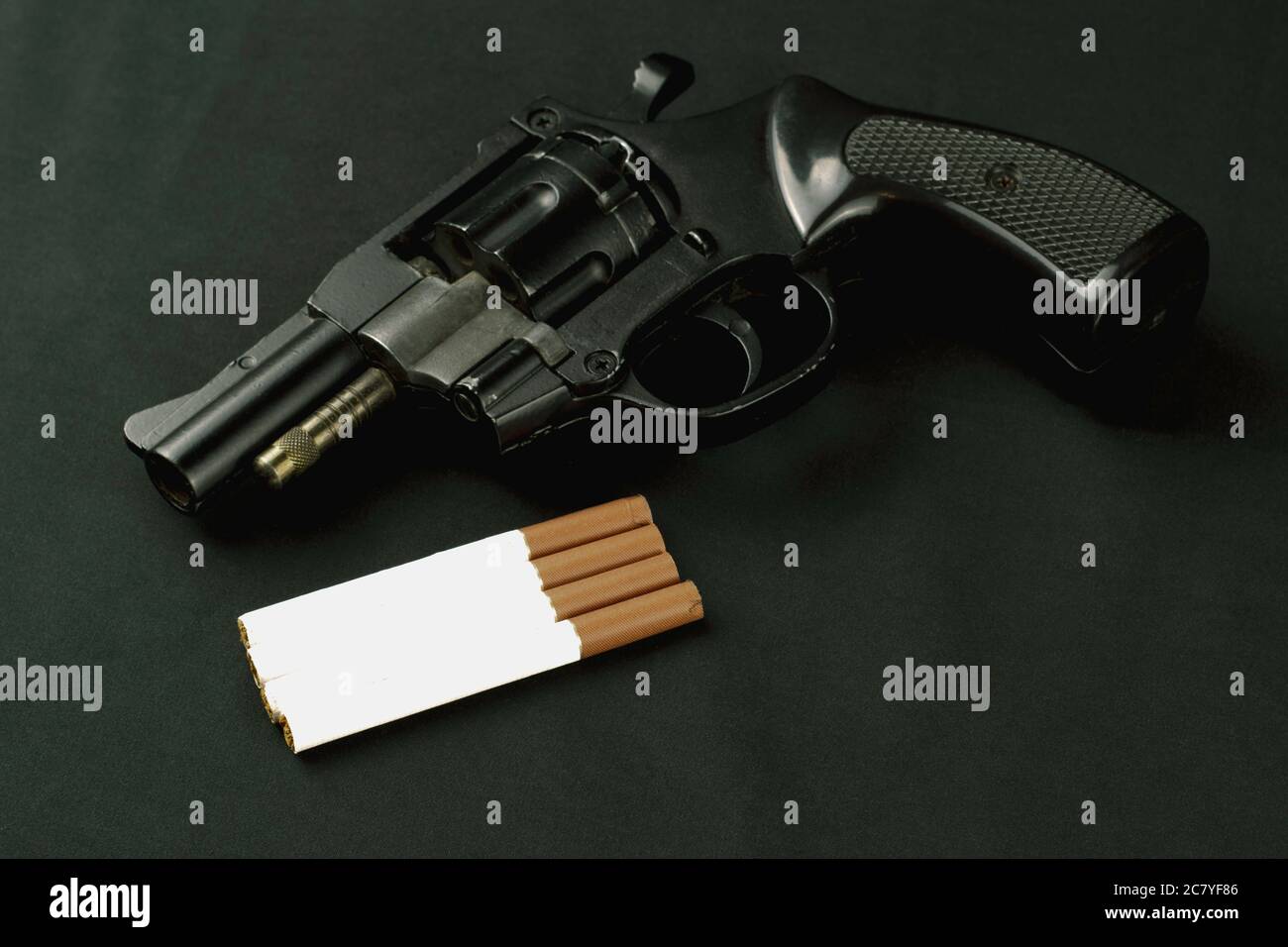 concept smoking - suicide pistol lying on a dark background next to ...