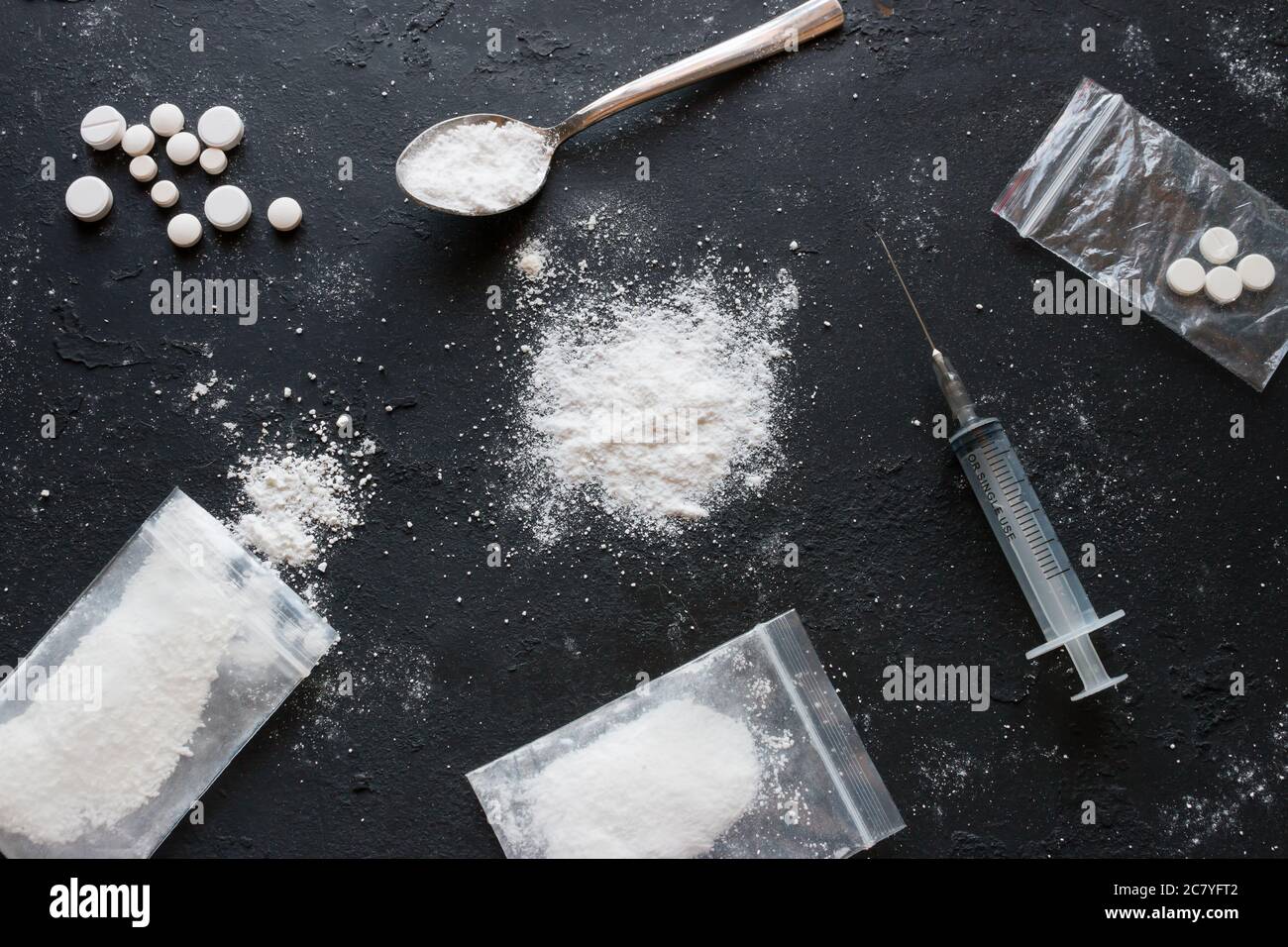 Set of different drugs - powder and pills and a syringe on a black ...