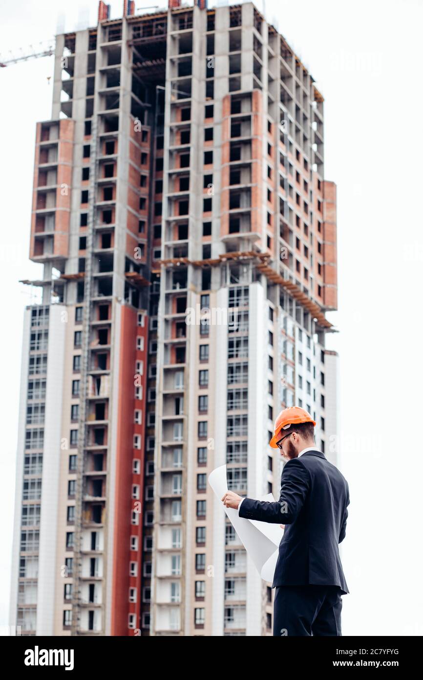 Portrait of an architect builder studying layout plan of the rooms ...