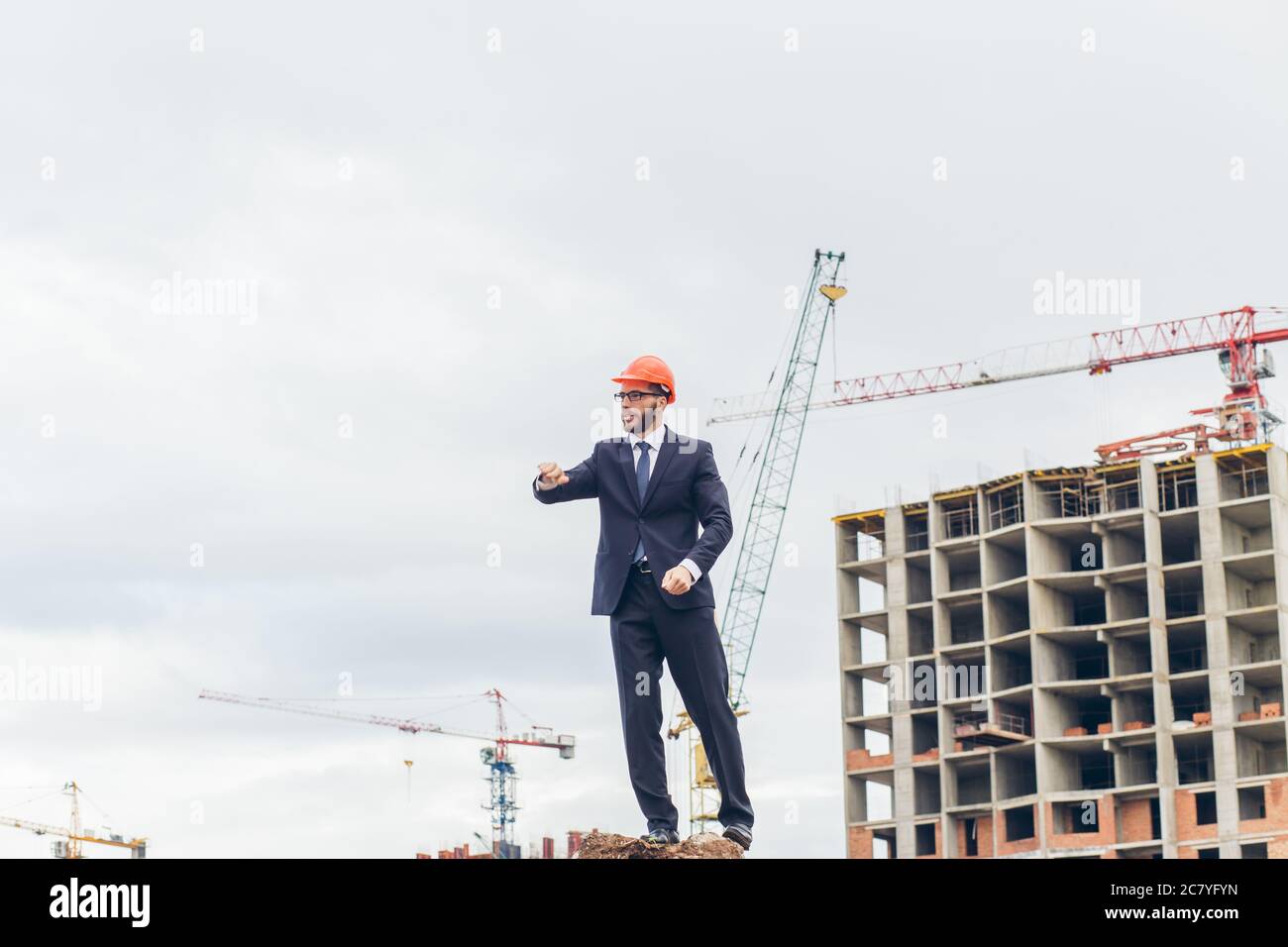 Engineer man in helmet and jacket controlling outdoor construction site ...