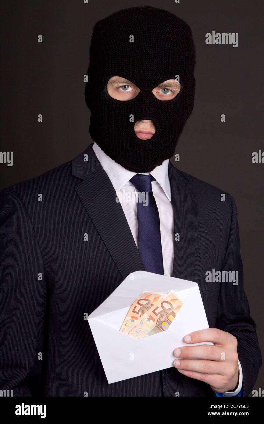 bribery concept - man in business suit and black mask holding envelope ...