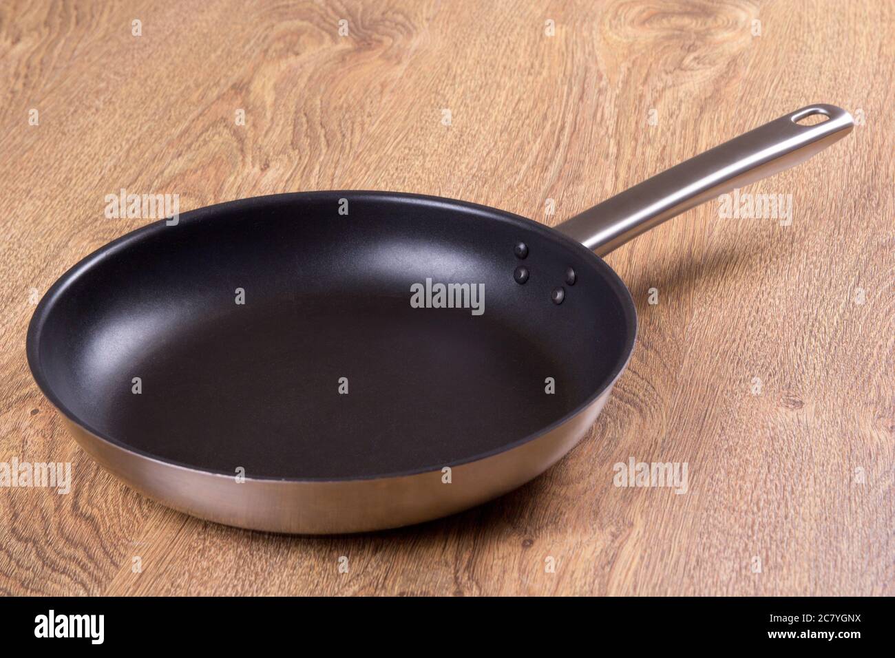 silver frying pan on wooden table background Stock Photo - Alamy