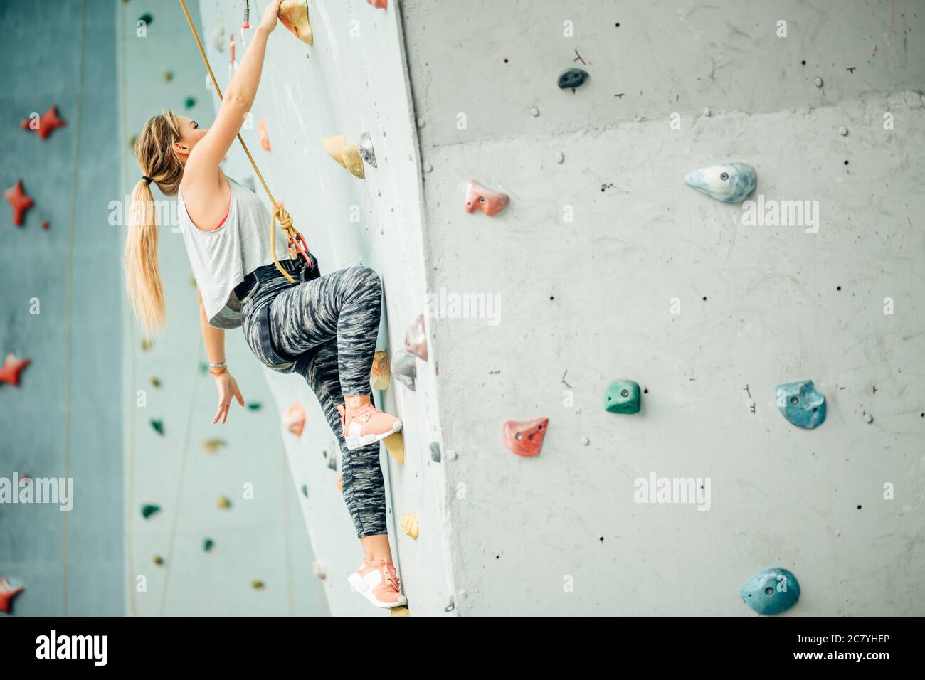 Beautiful young woman starts to climbing big artificial wall Stock ...